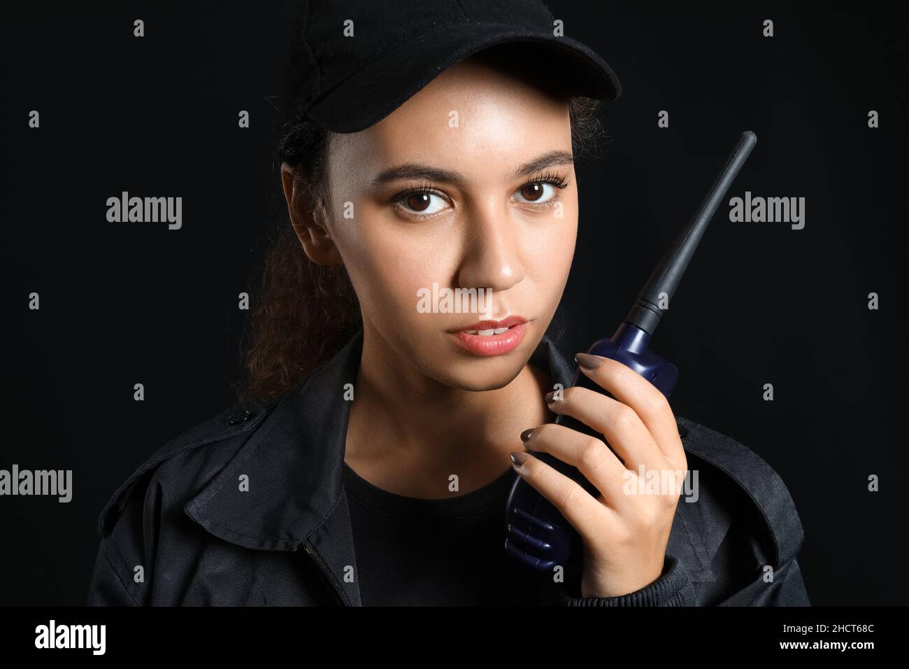 African-American female security guard with radio transmitter on dark ...