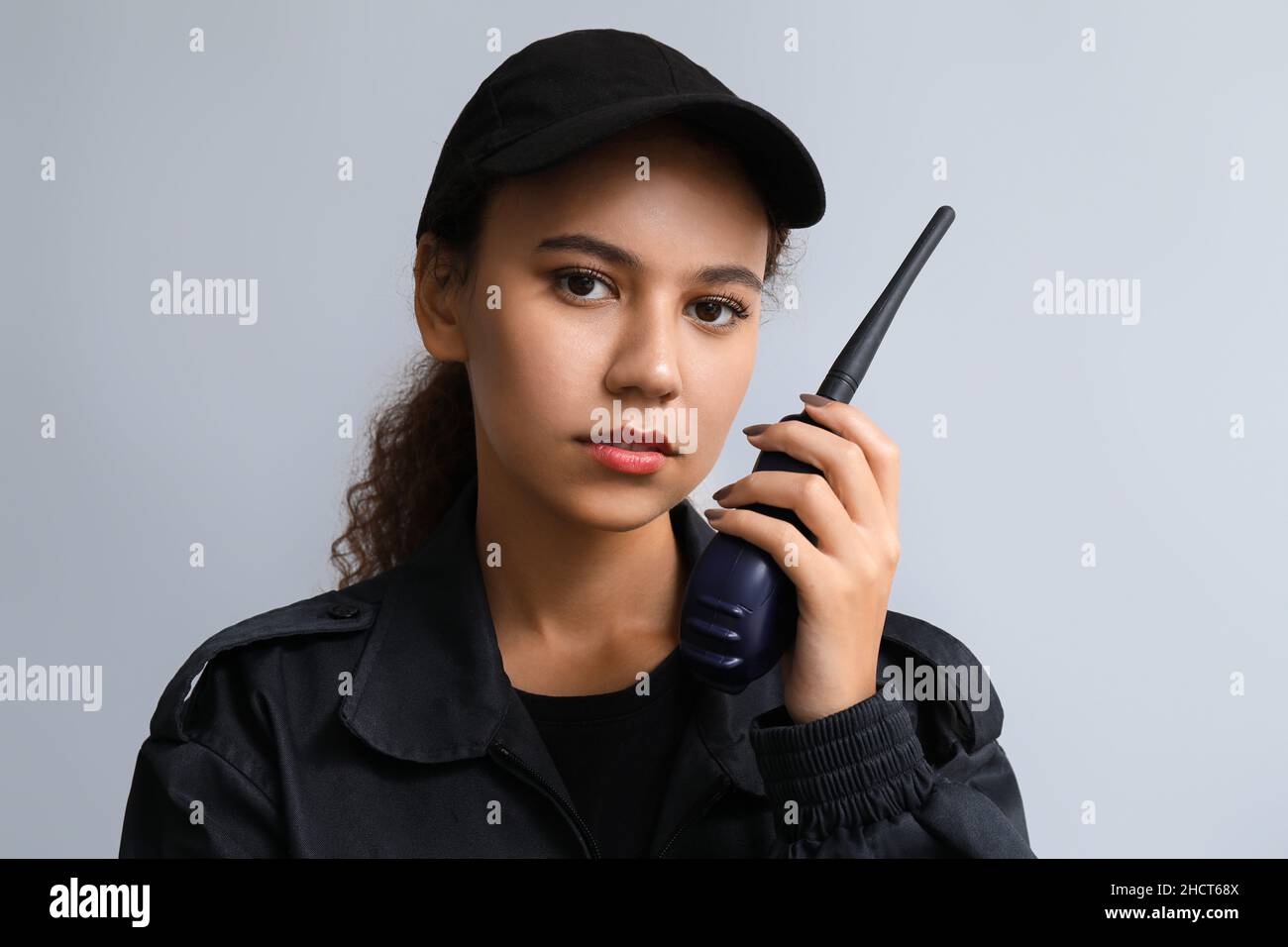 African-American female security guard with radio transmitter on light ...