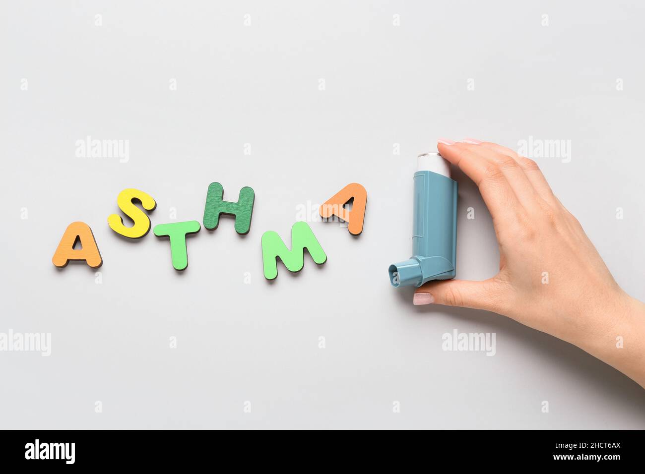 Female hand with modern inhaler and word ASTHMA on grey background ...