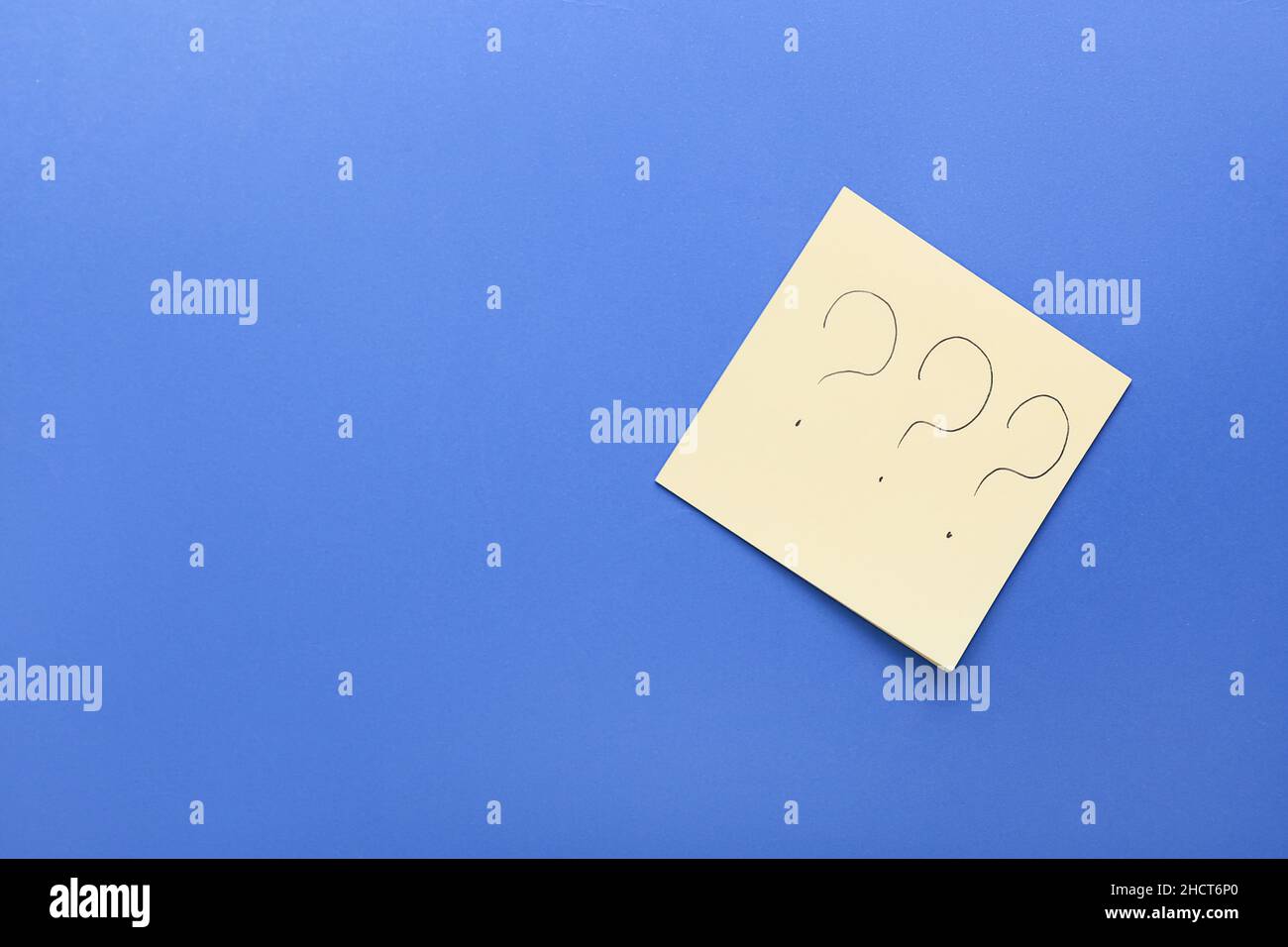 Sticky note with question marks on blue background Stock Photo - Alamy