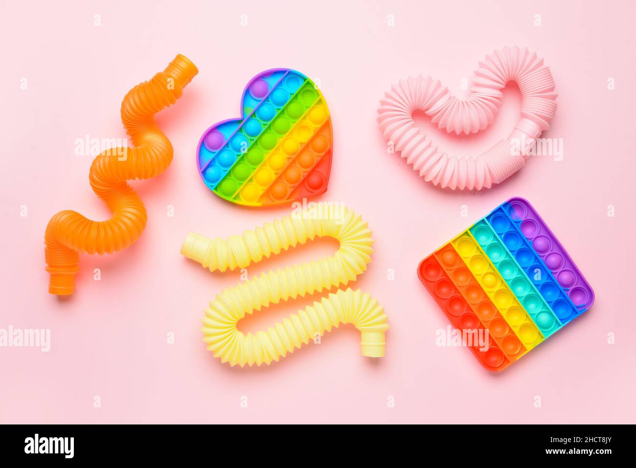 Colorful Pop Tubes and Pop it fidget toys on pink background Stock ...
