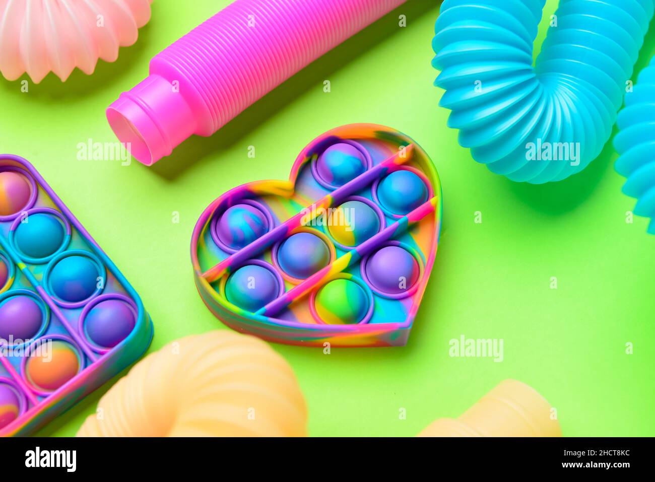 Colorful Pop Tubes and Pop it fidget toys on green background Stock ...