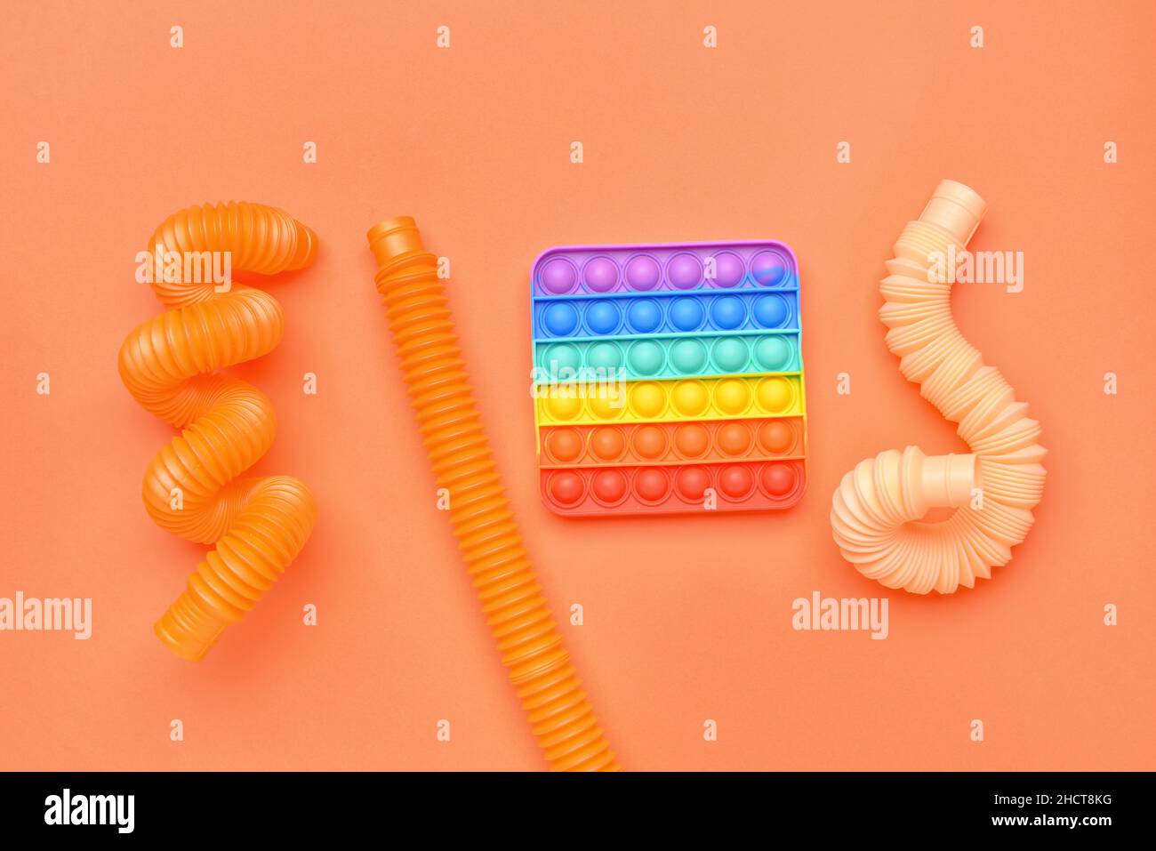 Colorful Pop Tubes and Pop it fidget toy on orange background Stock ...