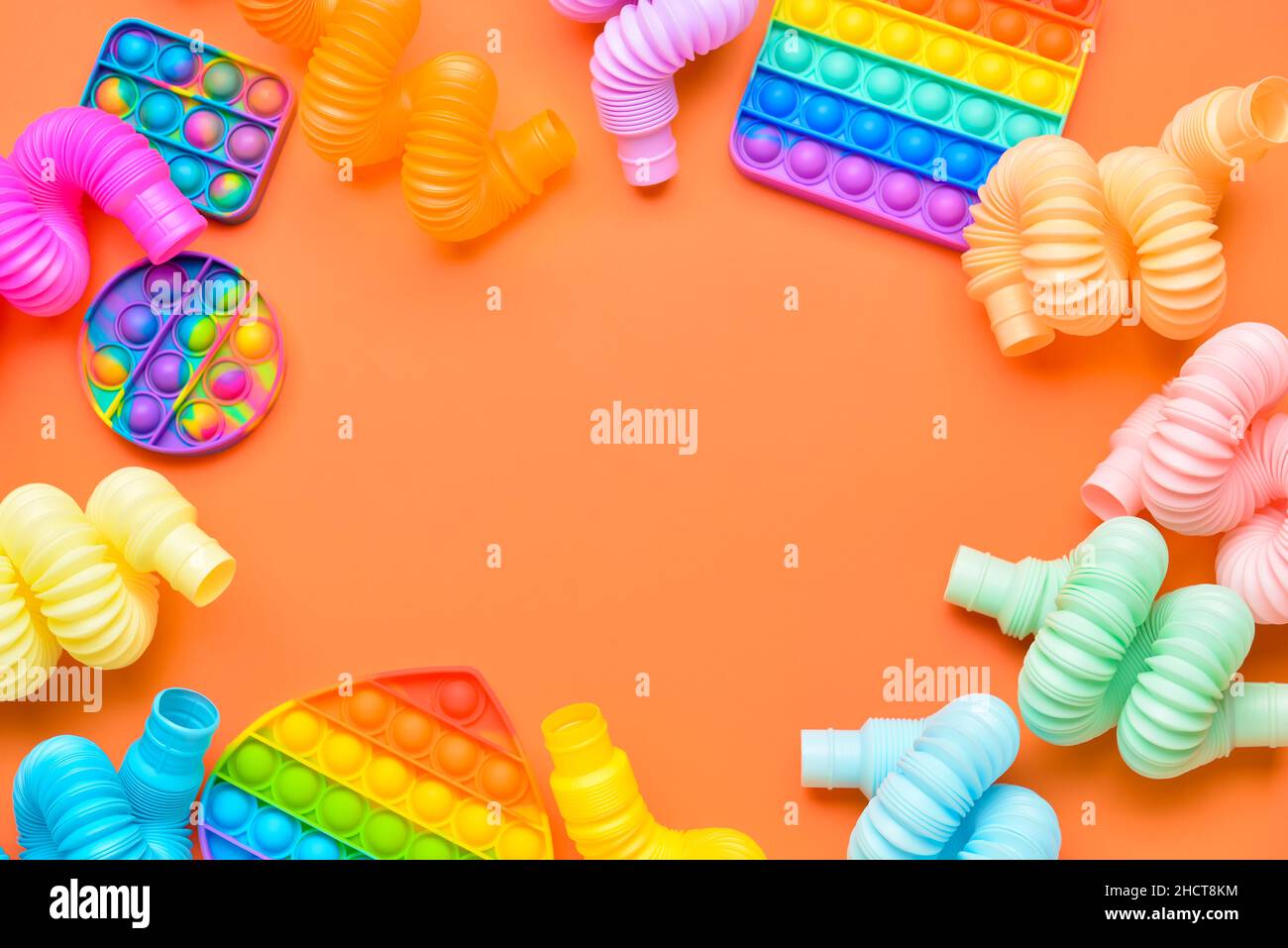 Frame made of colorful Pop Tubes and Pop it fidget toys on orange ...