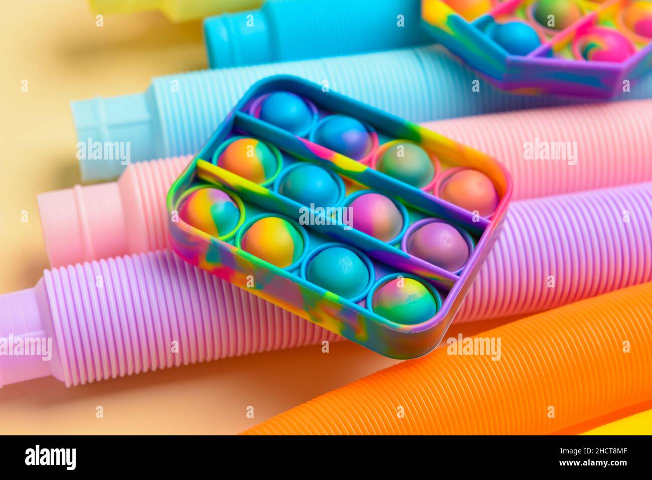 Colorful Pop Tubes and Pop it fidget toys on yellow background Stock ...