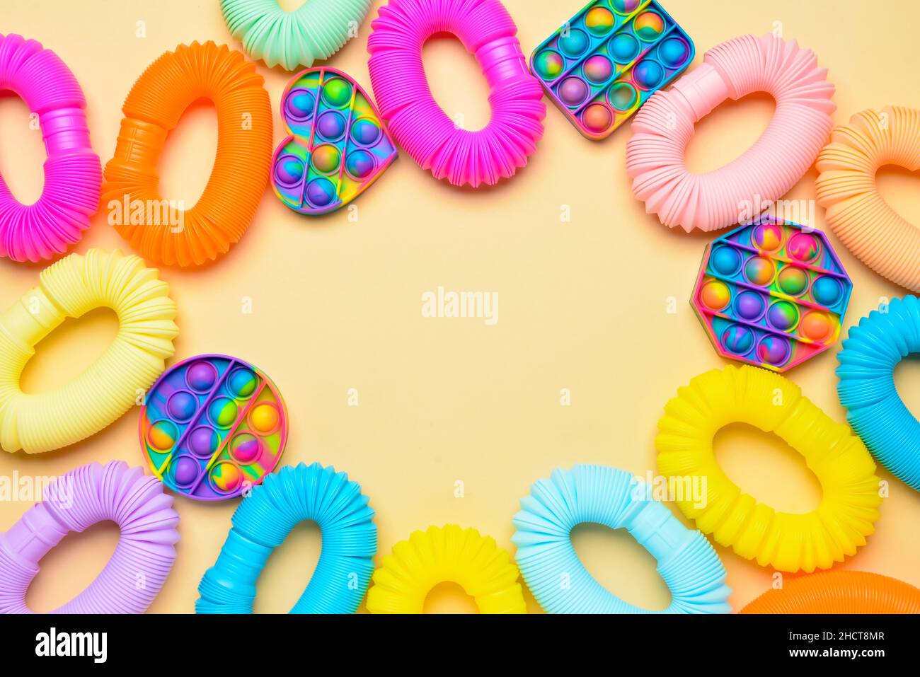 Frame made of colorful Pop Tubes and Pop it fidget toys on yellow ...