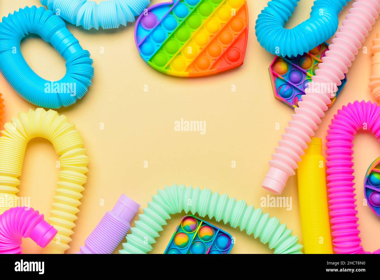 Frame made of colorful Pop Tubes and Pop it fidget toys on yellow ...