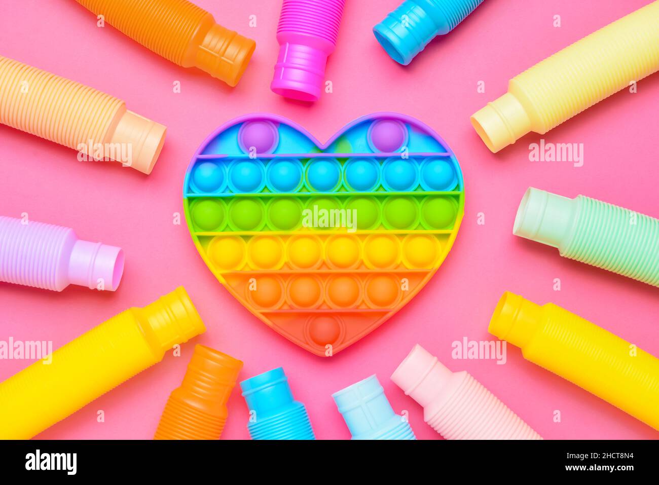 Colorful Pop Tubes and Pop it fidget toy on pink background Stock Photo ...