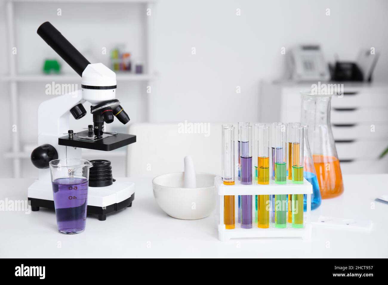 Modern microscope and chemical glassware on table in medical laboratory ...