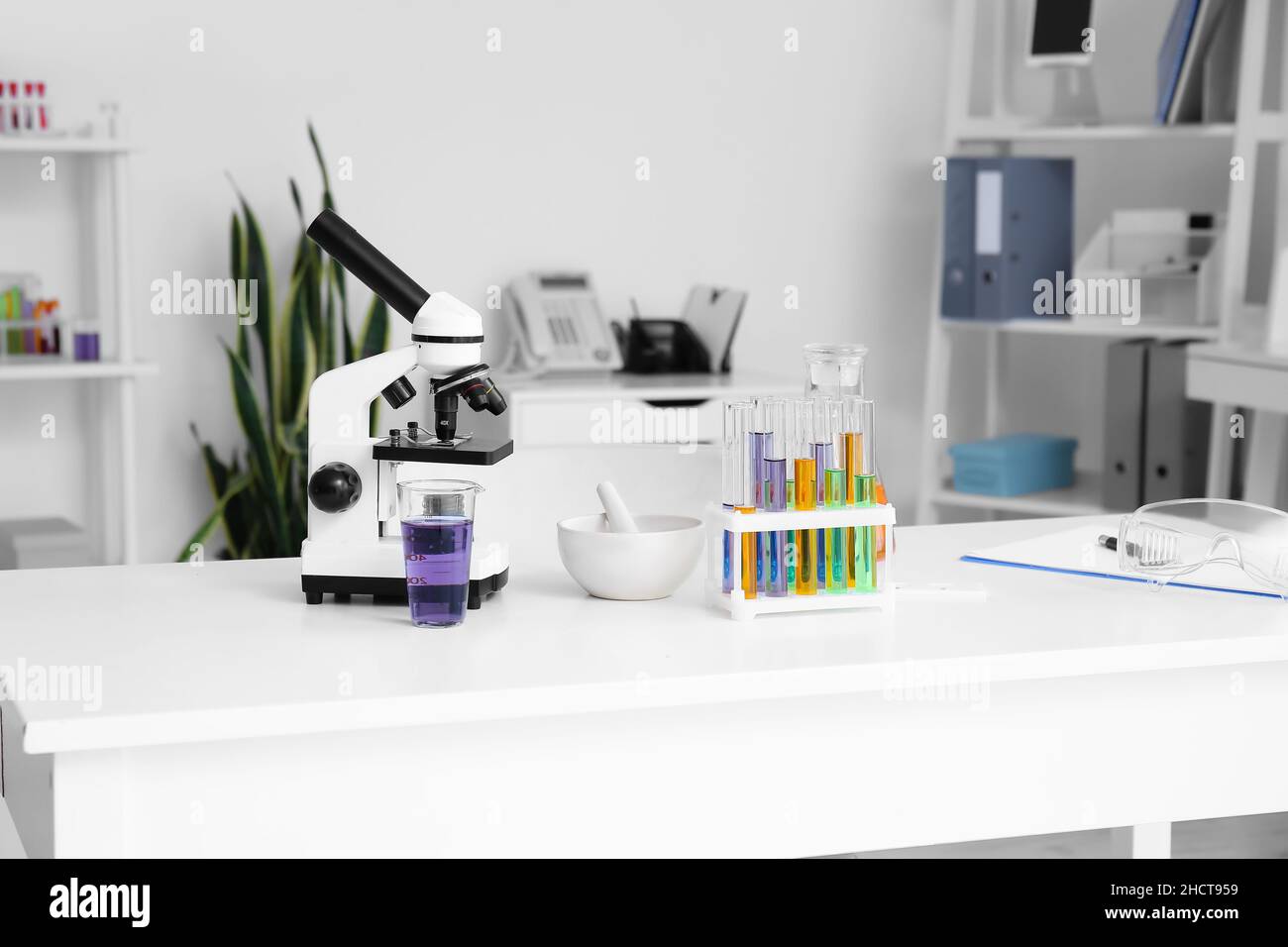 Modern microscope and chemical glassware on table in medical laboratory ...