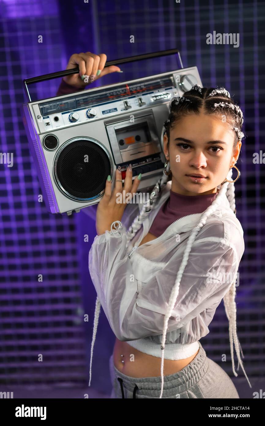 Portrait of a young girl with white braids with a boombox on her ...