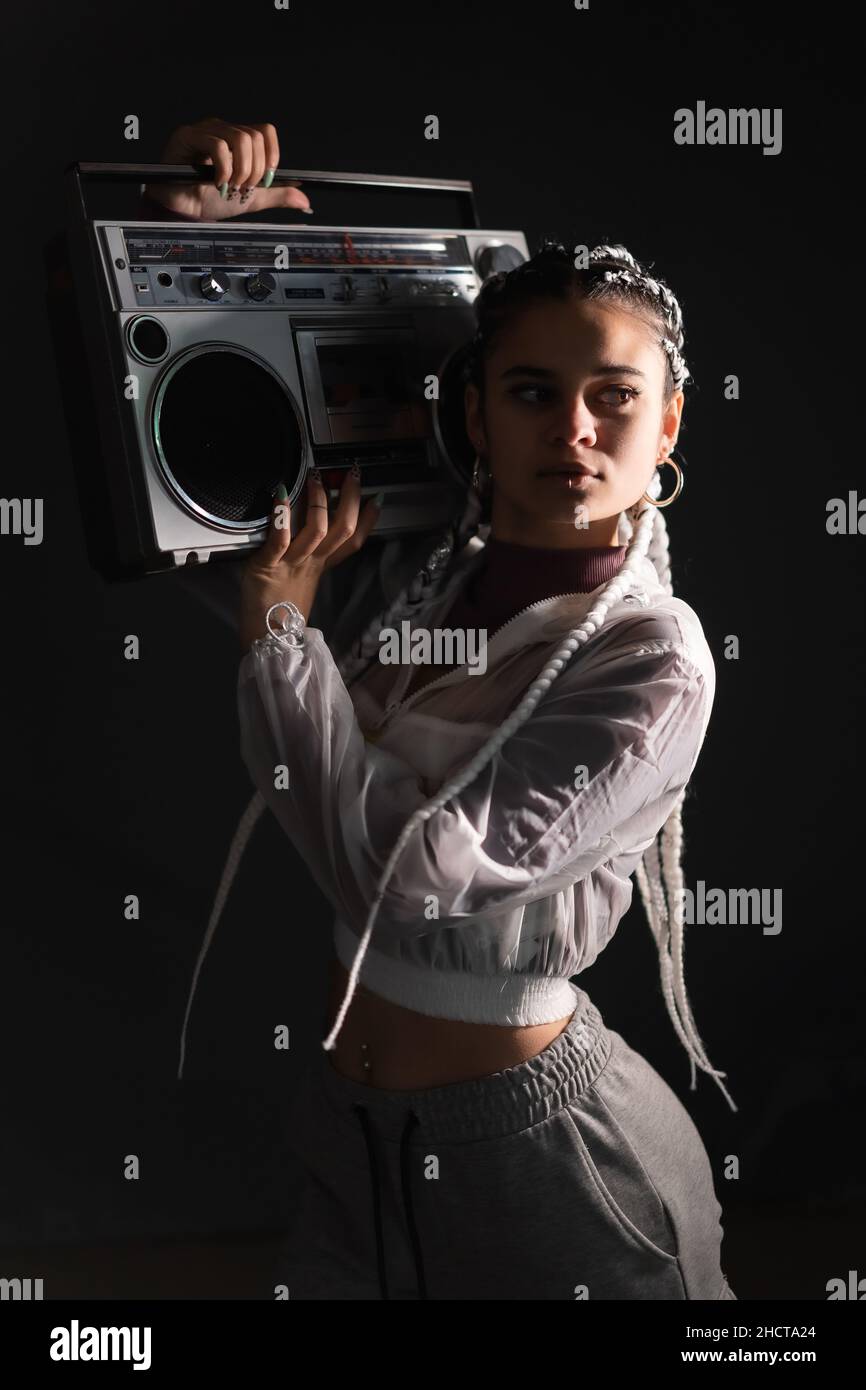 Portrait of a young girl with white braids with a boombox on her ...