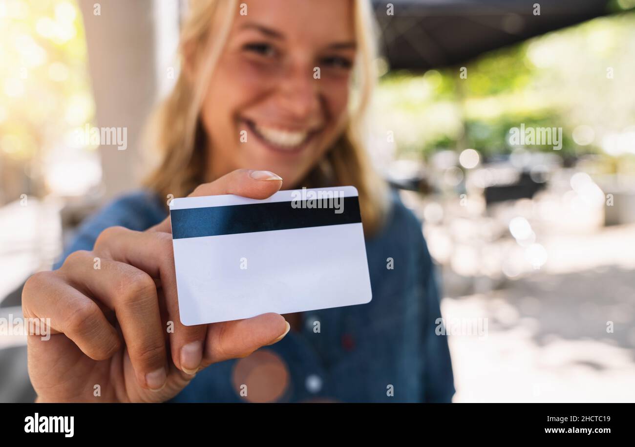 Happy young woman shows credit card in a cafe Stock Photo - Alamy