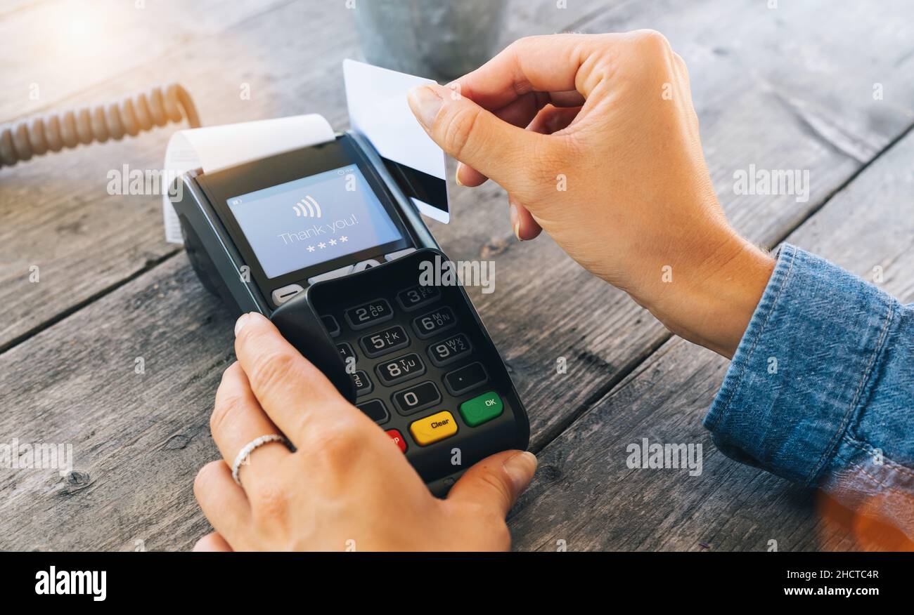 Hand swipe red credit through payment terminal Stock Photo - Alamy