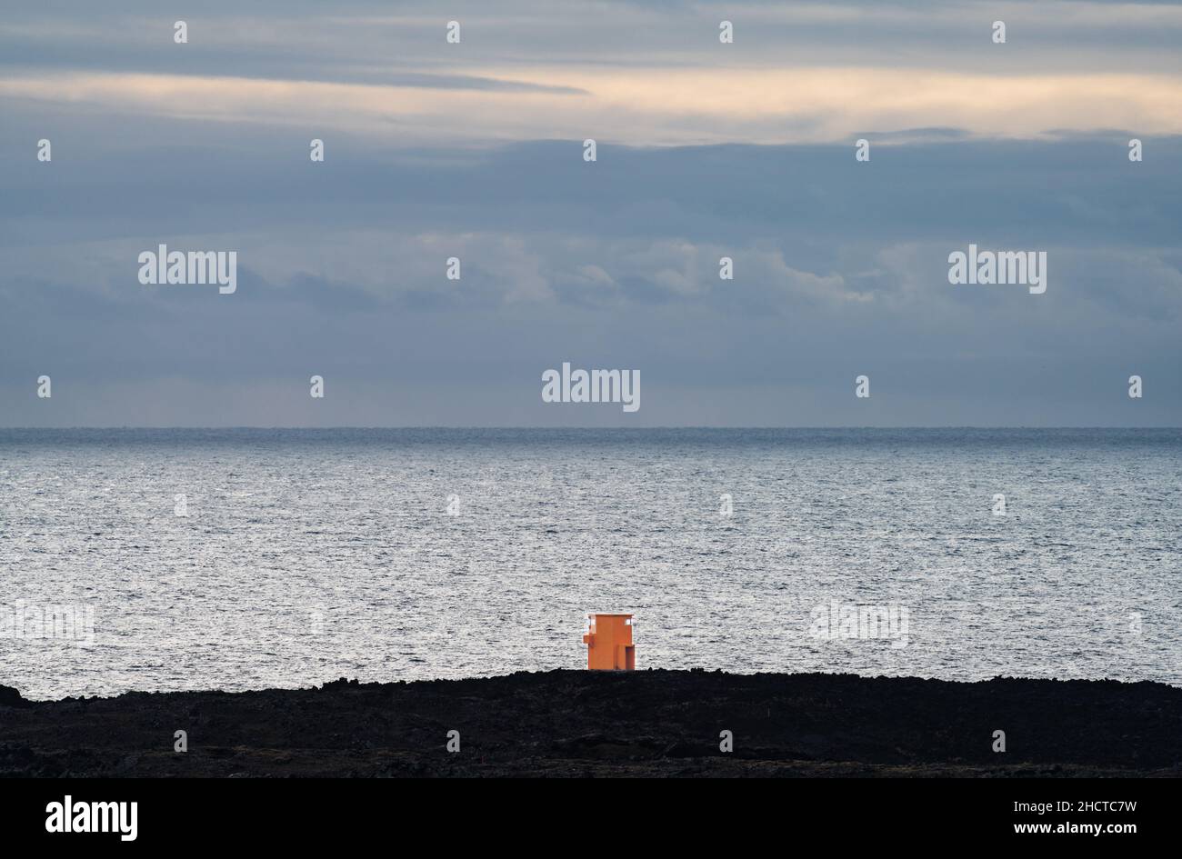 Orange tiny lighthouse facing the huge ocean Stock Photo - Alamy