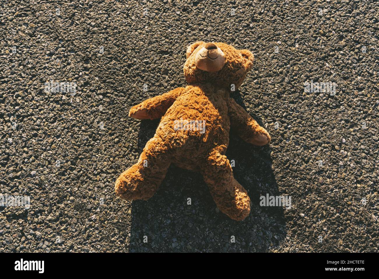 Lost teddy bear lying on the street after an accident, with skidmarks ...