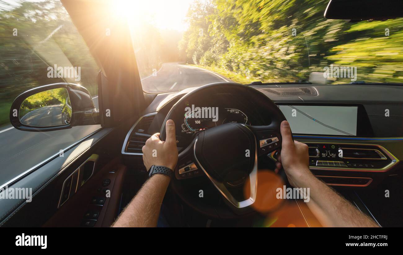 hands of car driver on steering wheel, road trip, driving on forest ...