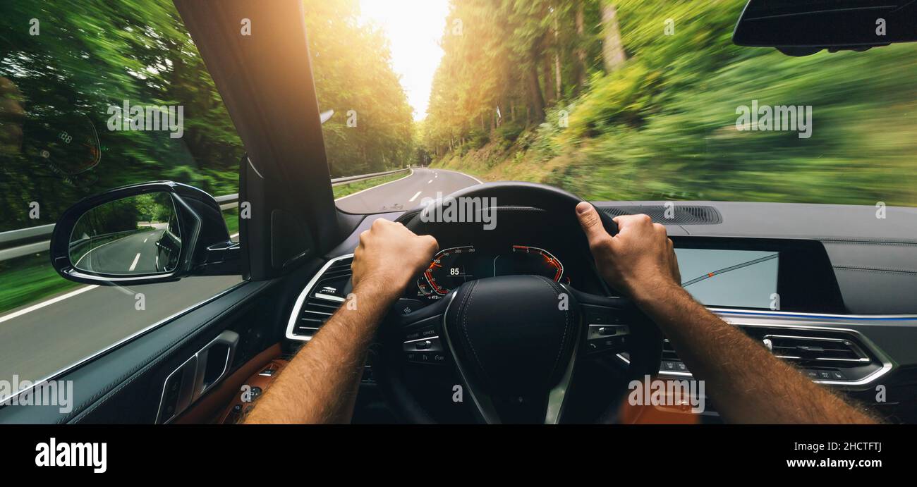 Hands of car driver on steering wheel, fast driving car at spring day ...
