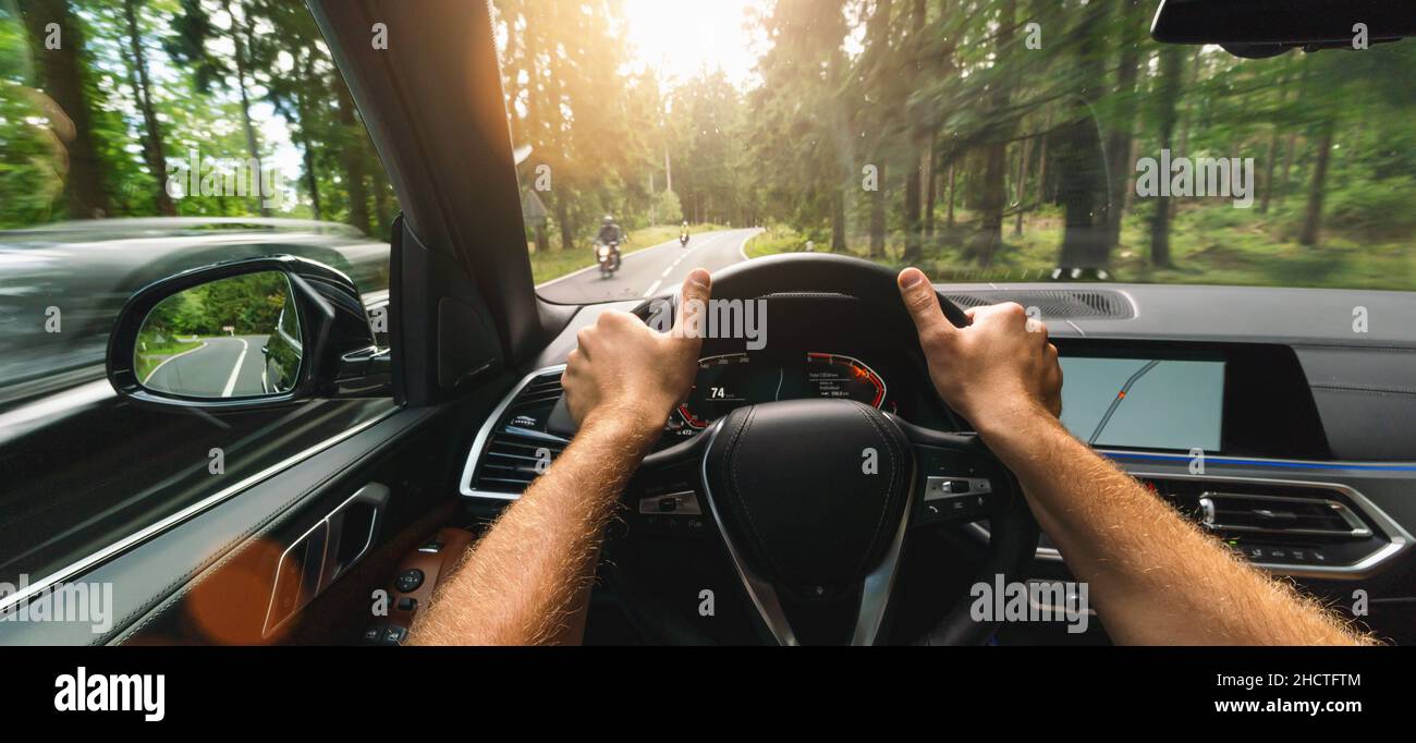 hands of car driver on steering wheel, road trip, driving on highway ...