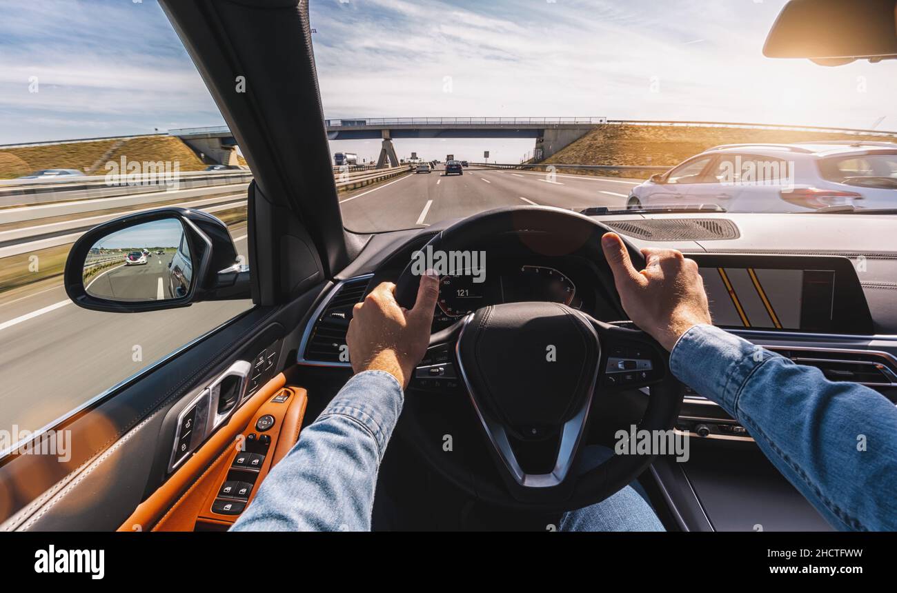 hands of car driver on steering wheel, road trip, driving on highway ...