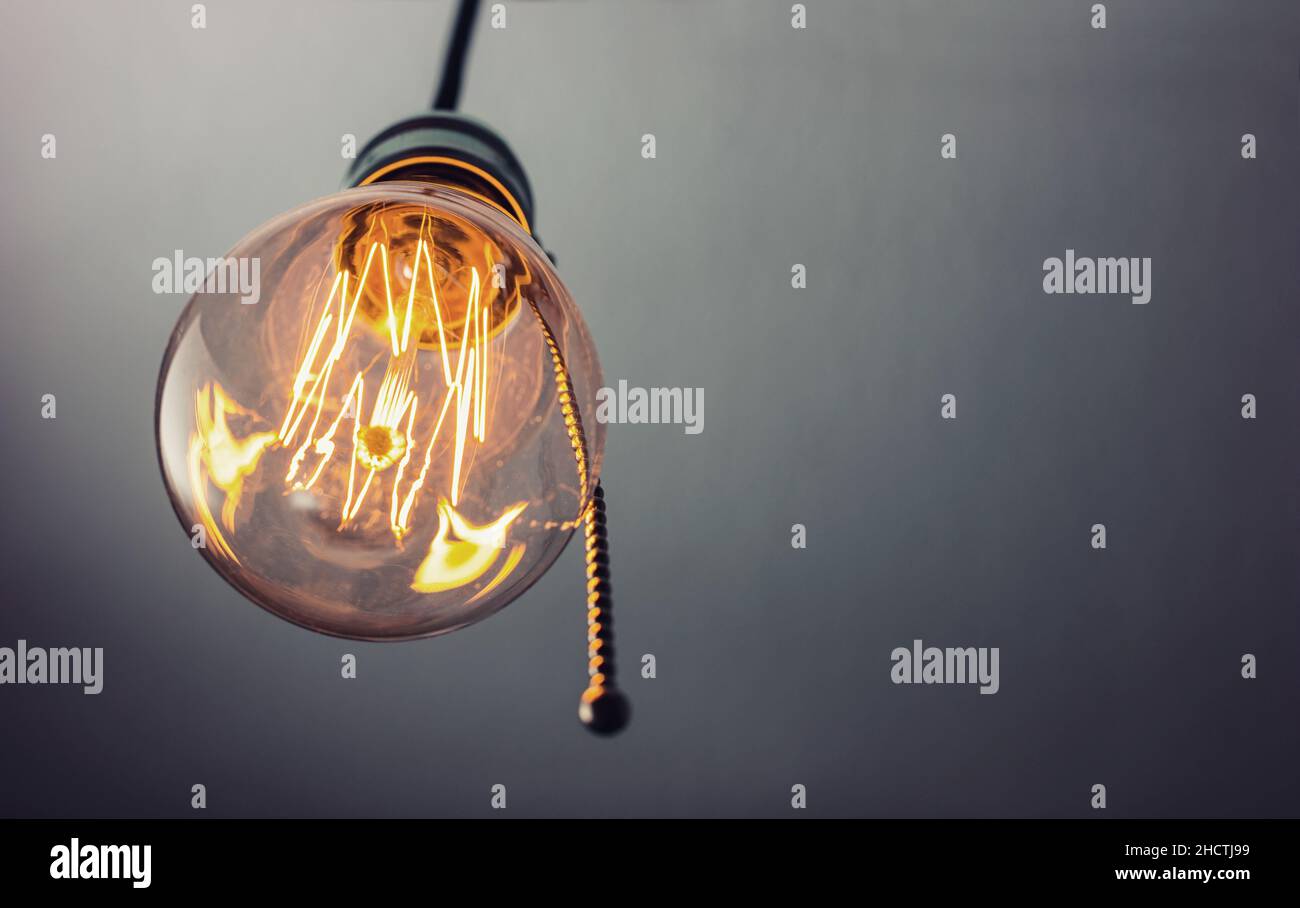 illuminated vintage hanging light bulb with pull switch Stock Photo - Alamy