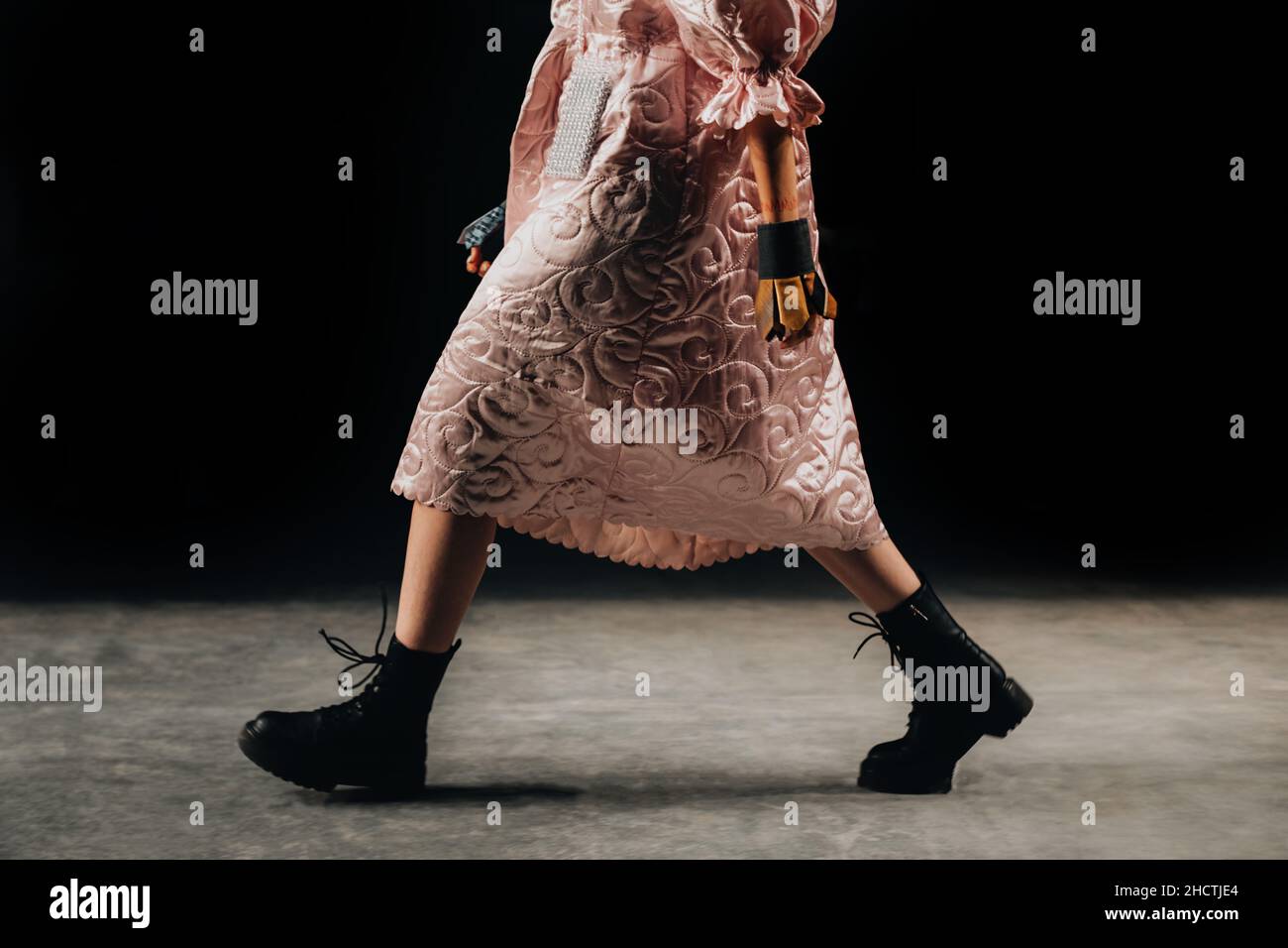 A cropped figure of a fashionable model walking the catwalk in a pink ...