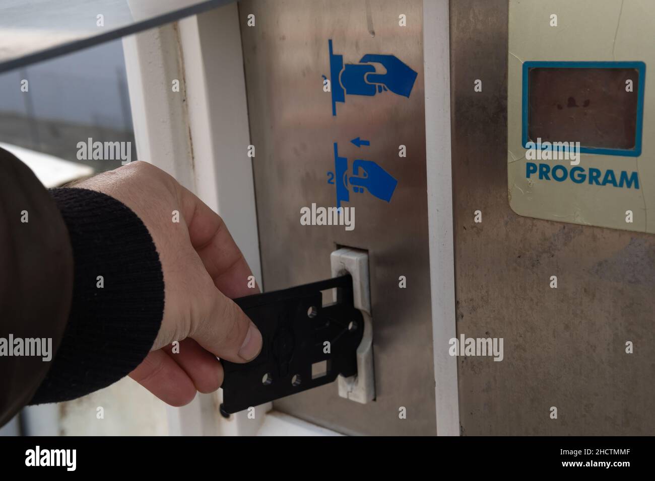 Close-up of a caucasian hand inserting a black card, in a car wash ...