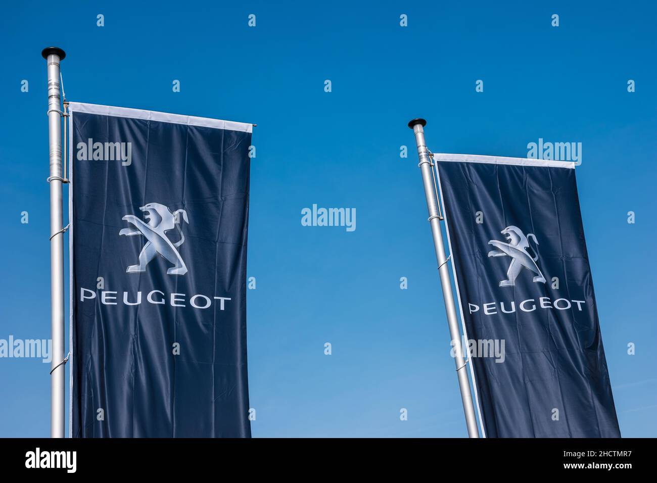 Peugeot flags against blue sky at the Peugeot Store. Peugeot is a ...