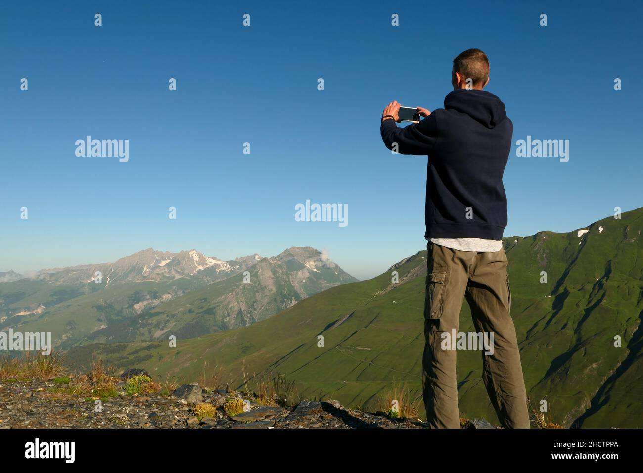 A man taking a picture with a smartphone in nature. Back hiker, at the ...
