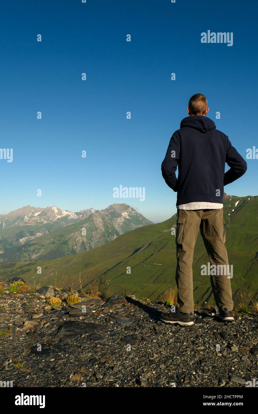 A man from the back, facing green mountains. A hiker contemplates the ...