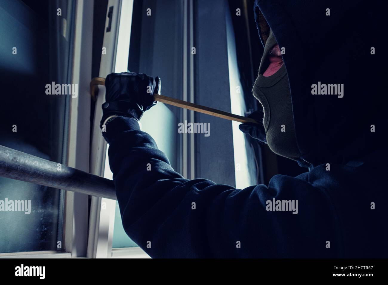 burglar using crowbar to break into a victim's house at night Stock ...