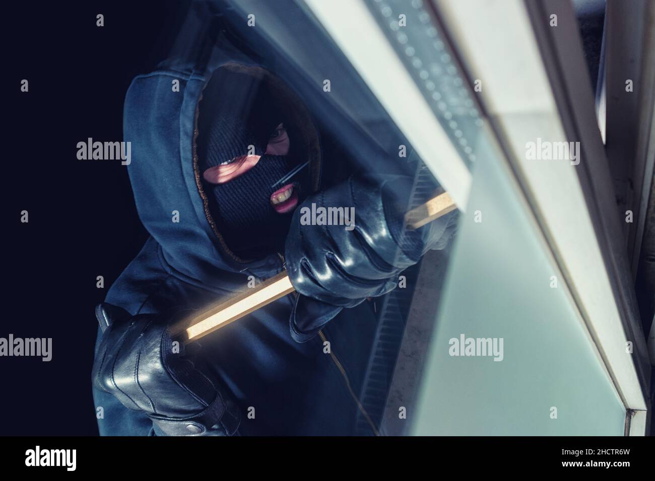 burglar using crowbar to break into a house window at night Stock Photo ...