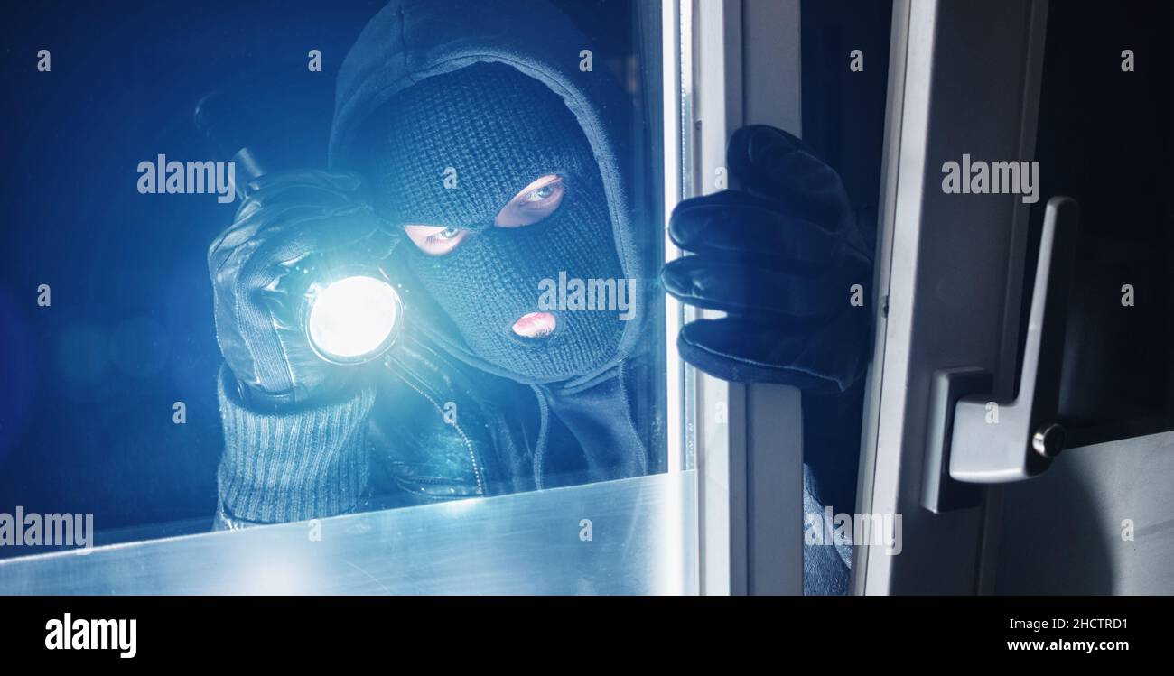 Burglar entering to house trough a window at night Stock Photo - Alamy