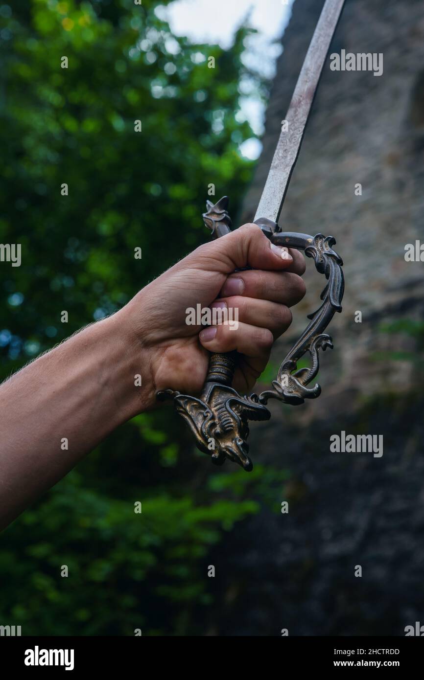 close-up of hand holding a sword in front of old castle Stock Photo - Alamy