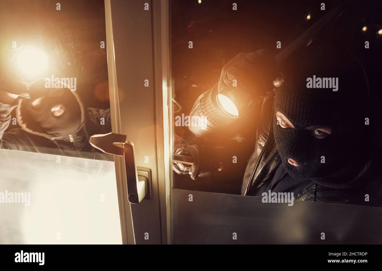 Two Burglar breaking in a window of a house at night Stock Photo - Alamy