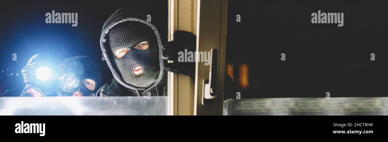 Burglar at night with flashlight at window of the house, with copy ...