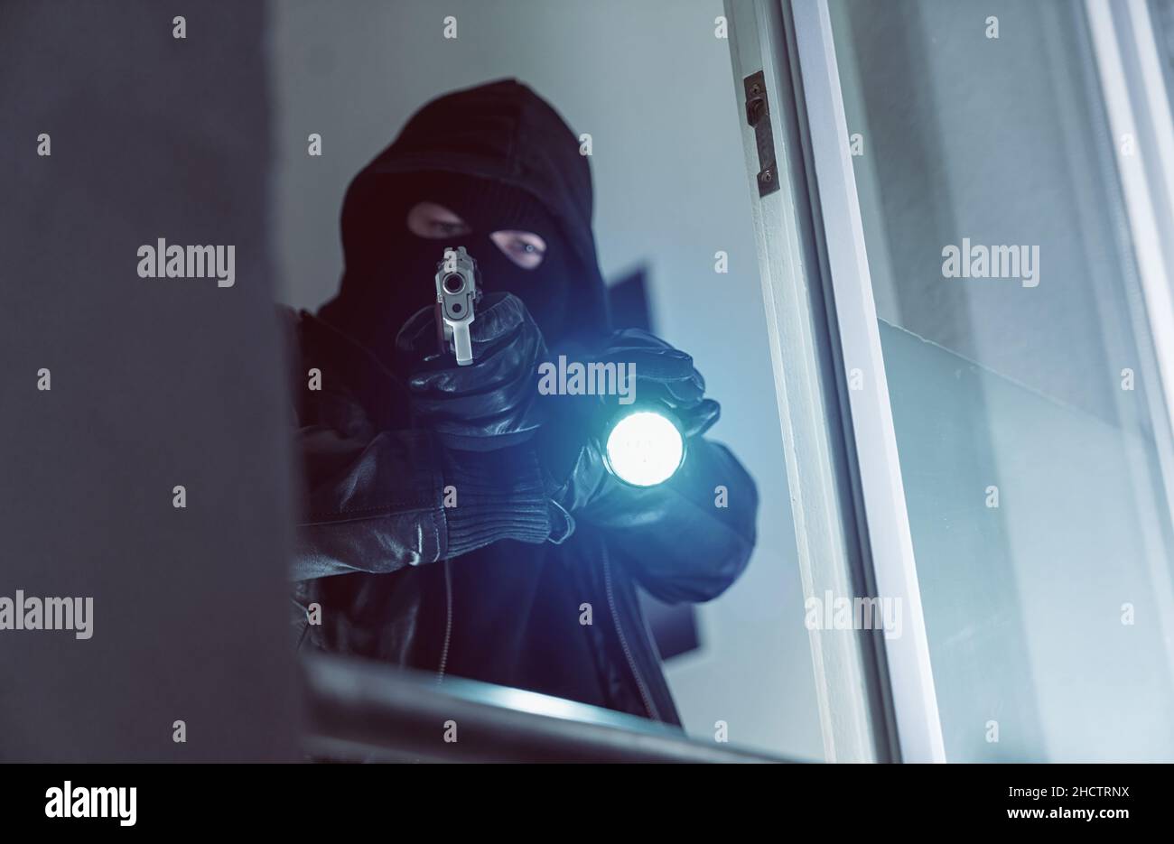 Terrorist or a Burglar pointing with a gun outside a window at night ...