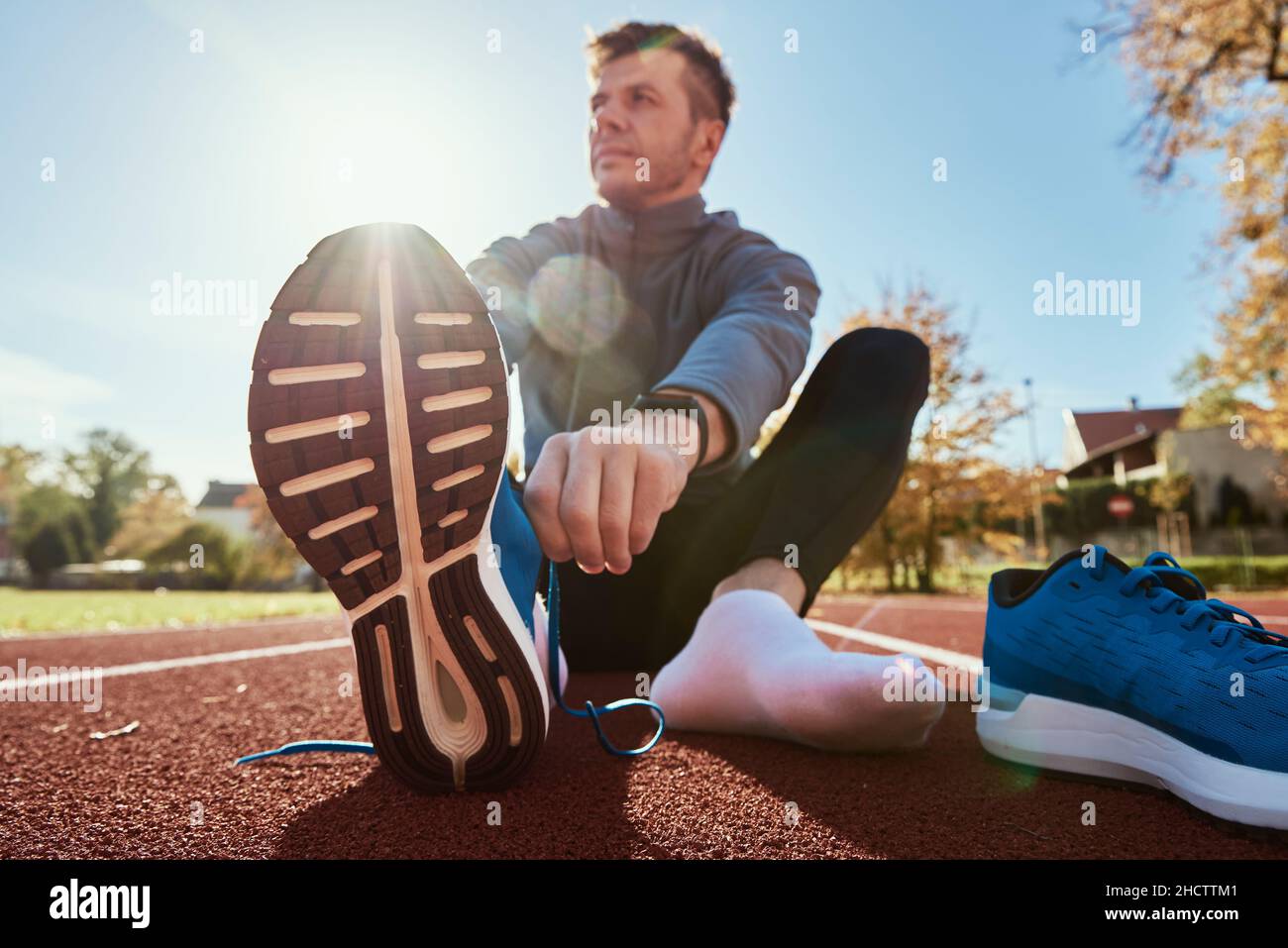 Male runner in blue sneakers get ready for run at stadium track, close ...