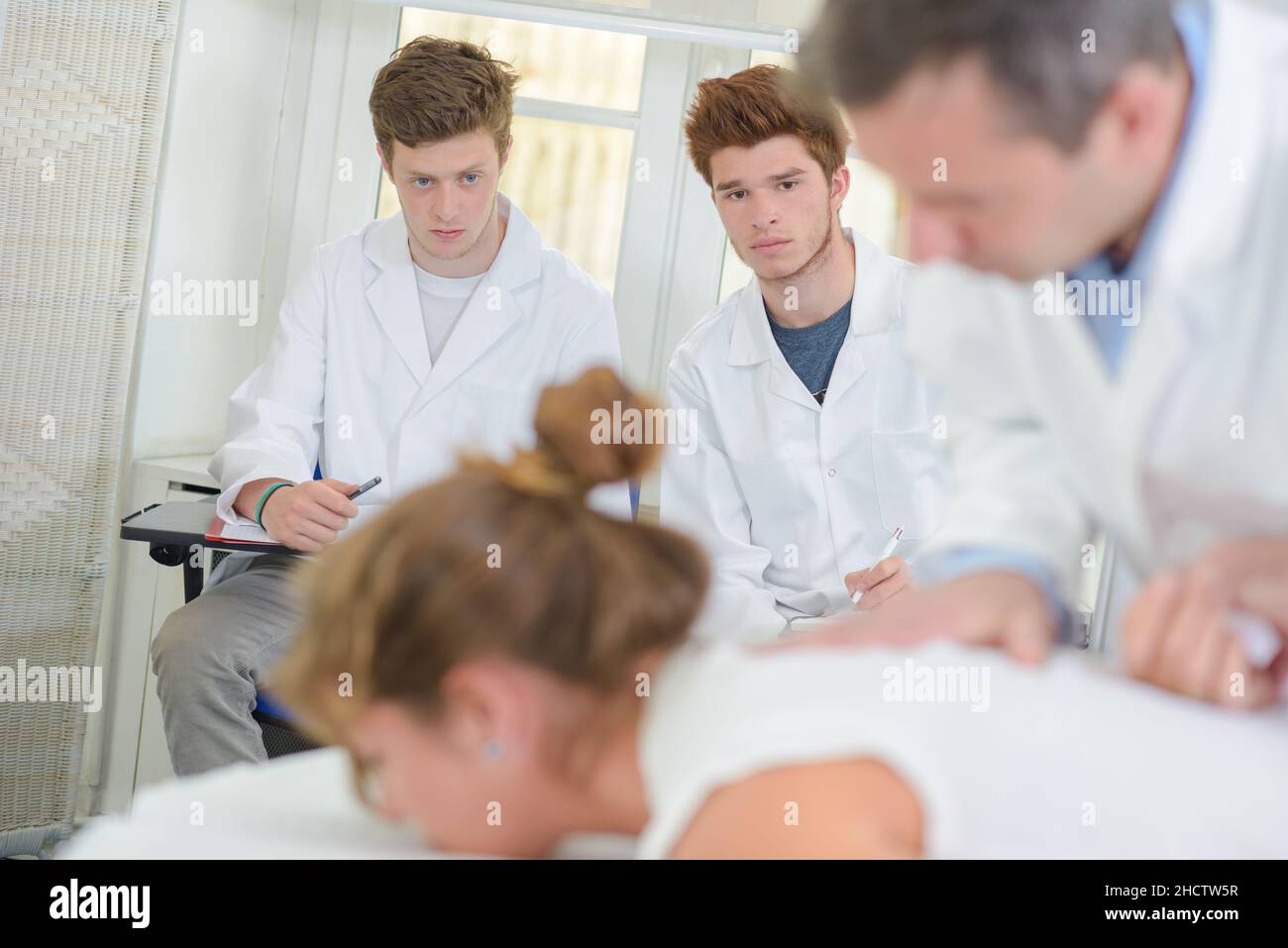 Students watching doctor work on patient's back Stock Photo - Alamy