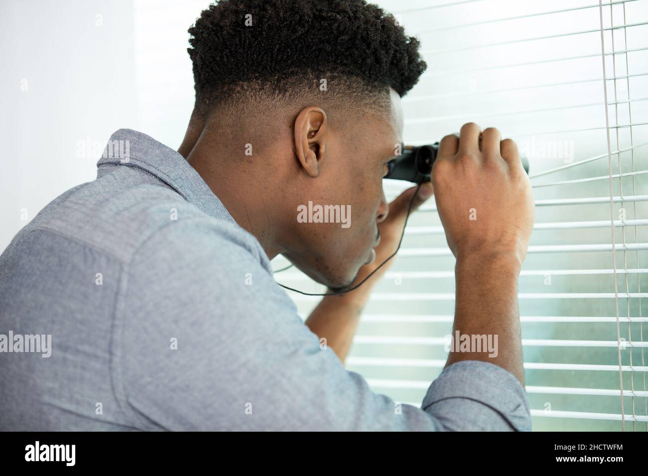 man outdoors looking through window blinds with binoculars Stock Photo ...