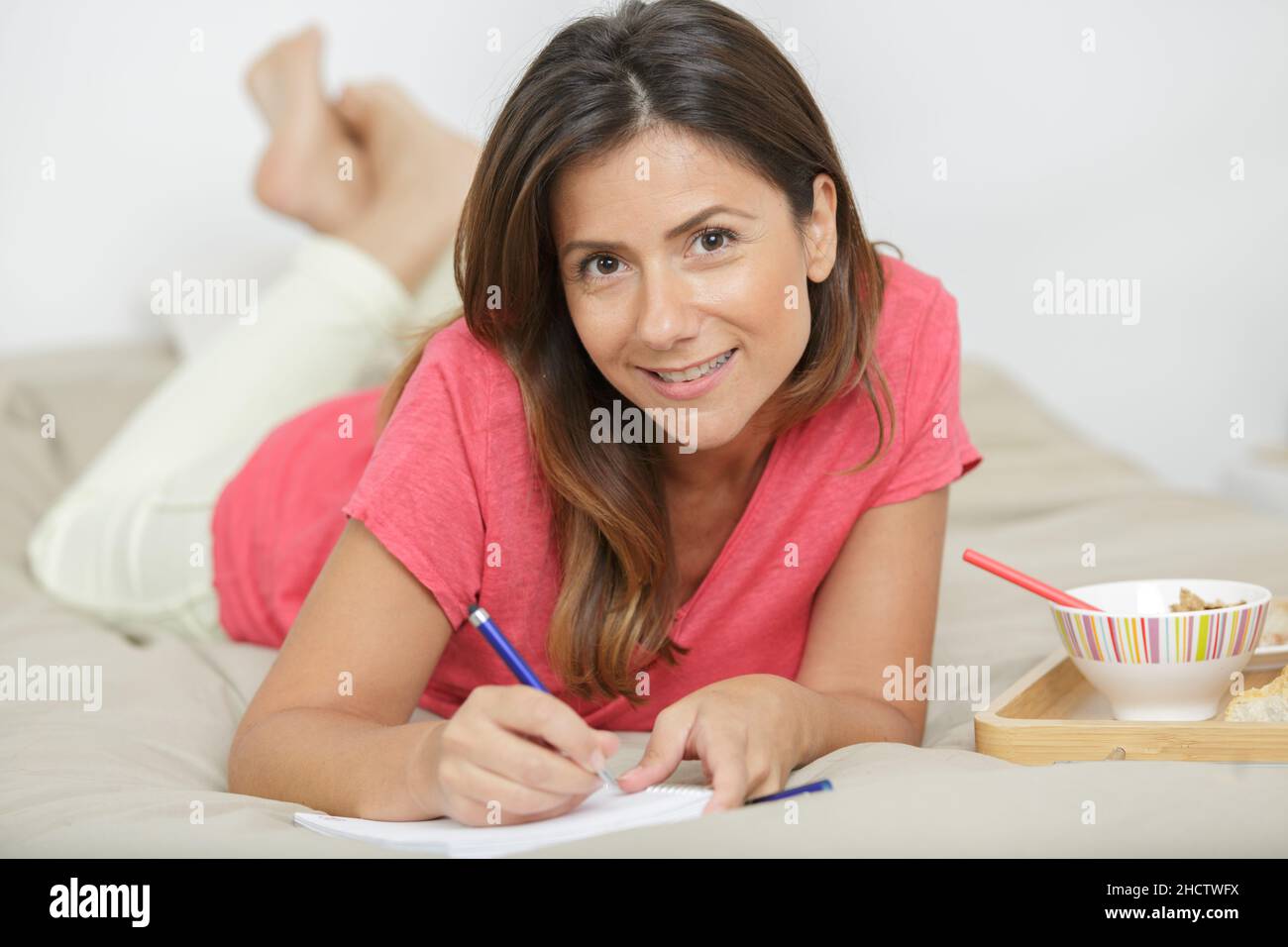 woman layed on bed with breakfast tray making notes Stock Photo - Alamy