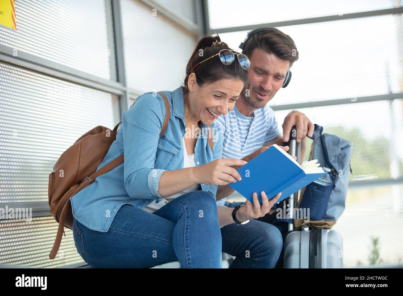 couple sitting at train station reading a book Stock Photo - Alamy