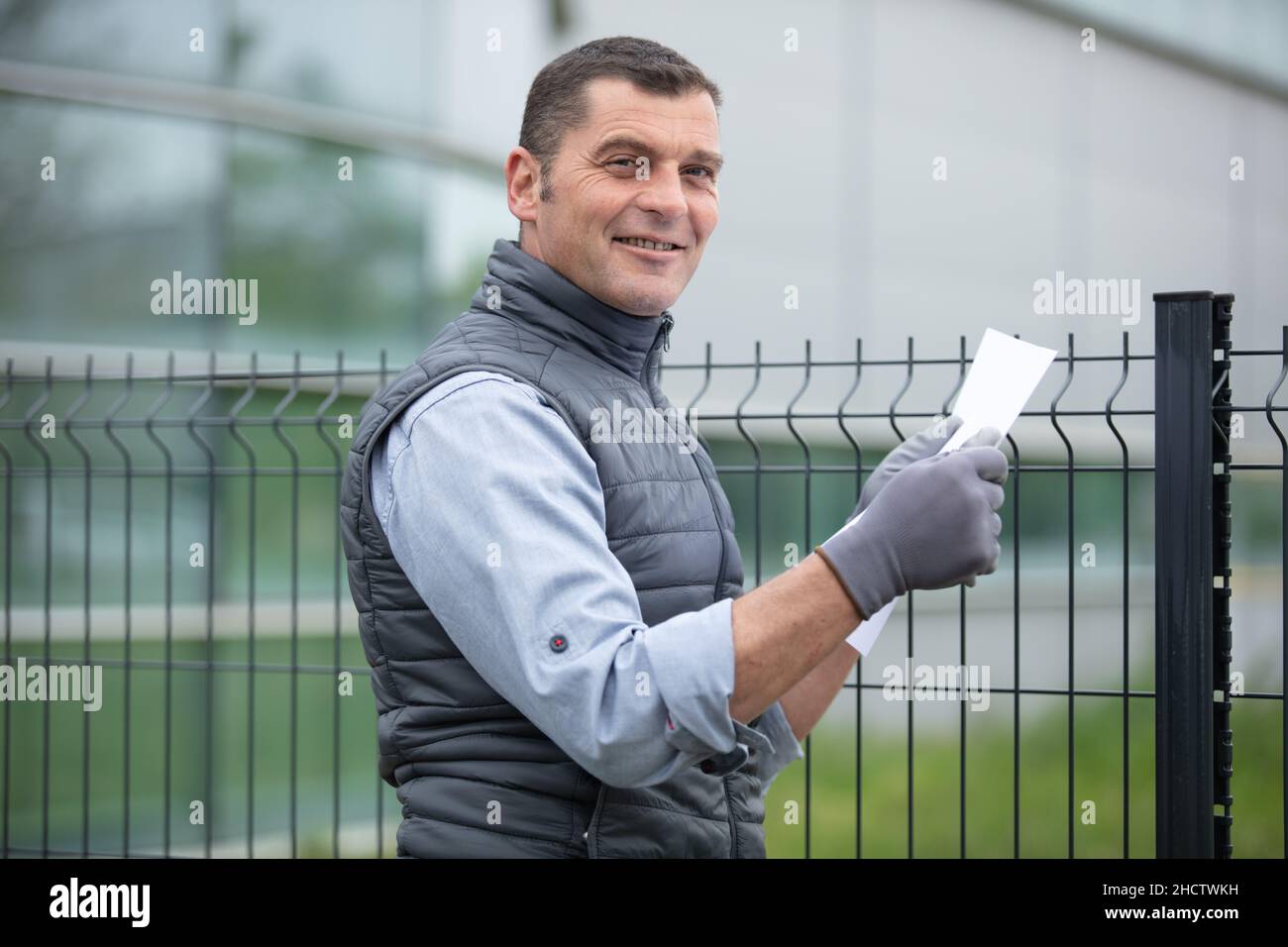 foreman looking at paperwork in front of metal fence Stock Photo - Alamy