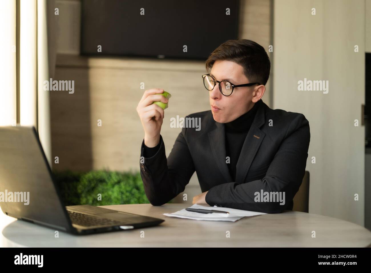 Businessman has a healthy snack apple while sitting in the office ...