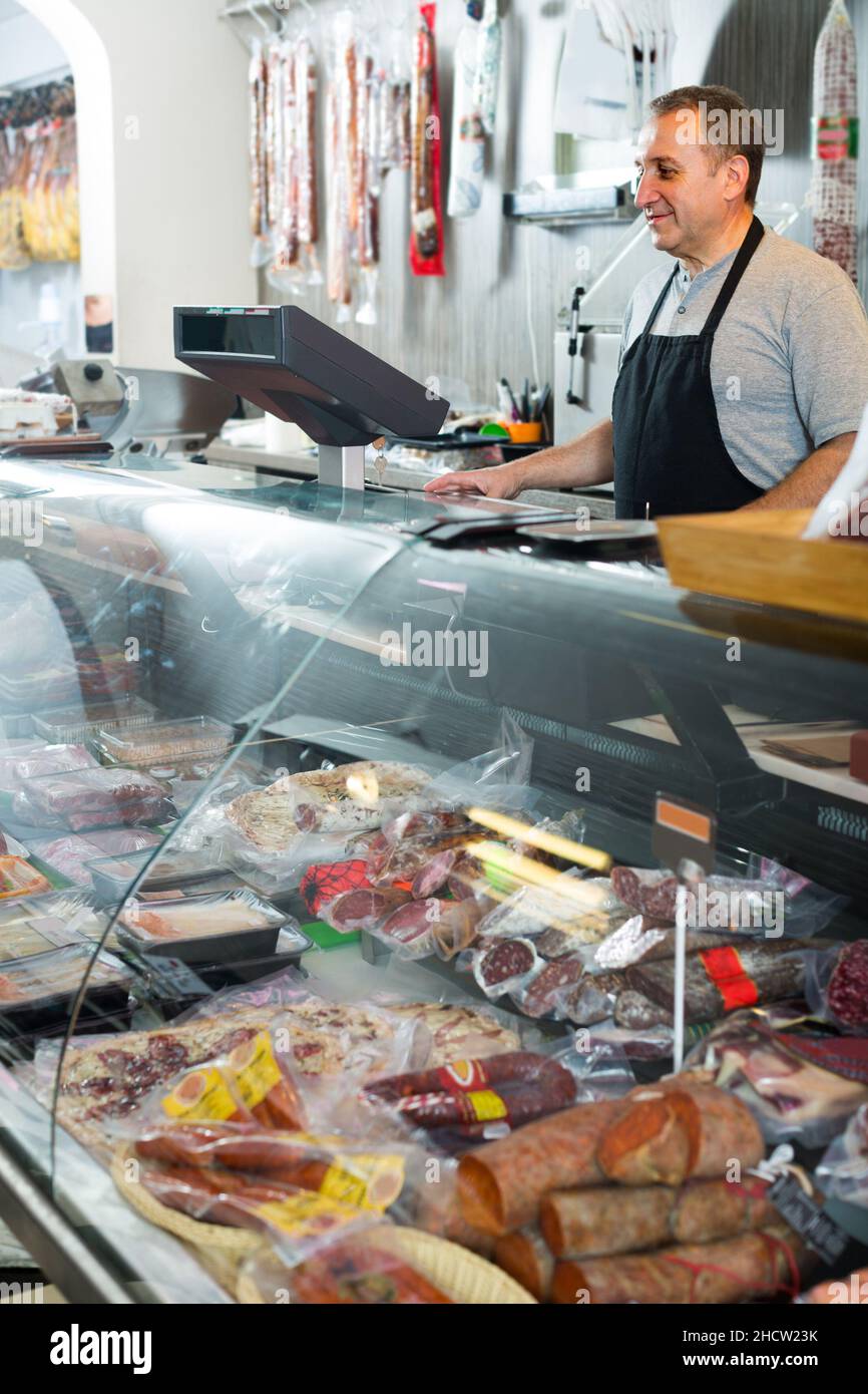 butcher with smoked meat at counter Stock Photo - Alamy