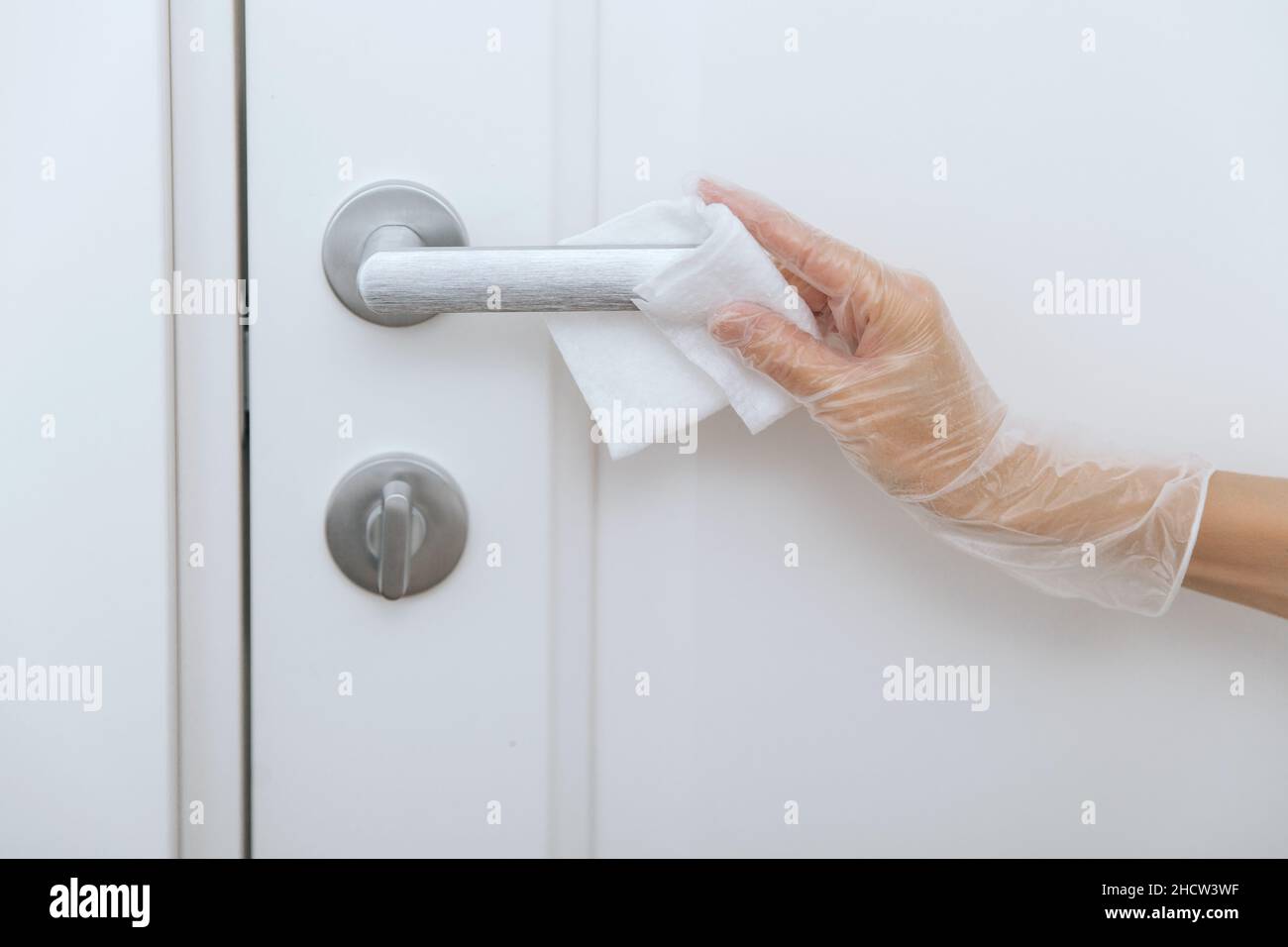 Cleaning door handles with wet wipe and white gloves. Woman hand using ...