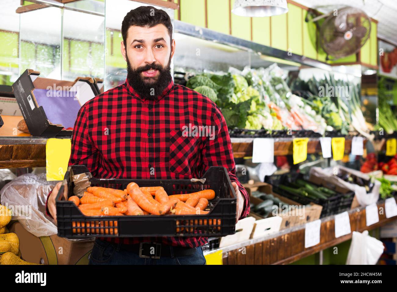 Male shop assistant demonstrating carrots Stock Photo - Alamy
