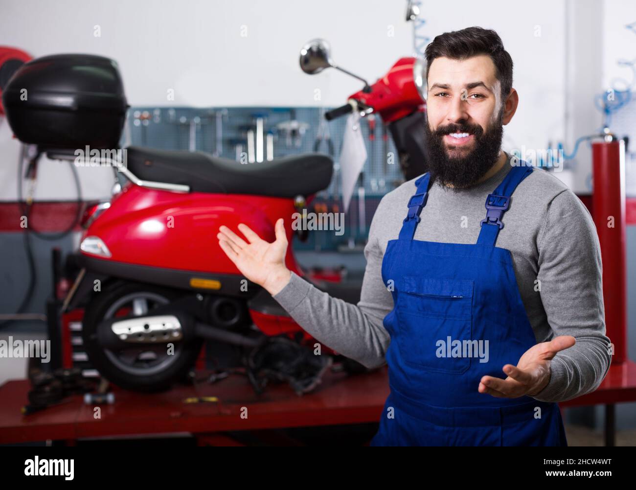 Worker demonstrating motorbikes in motorcycle workplace Stock Photo - Alamy