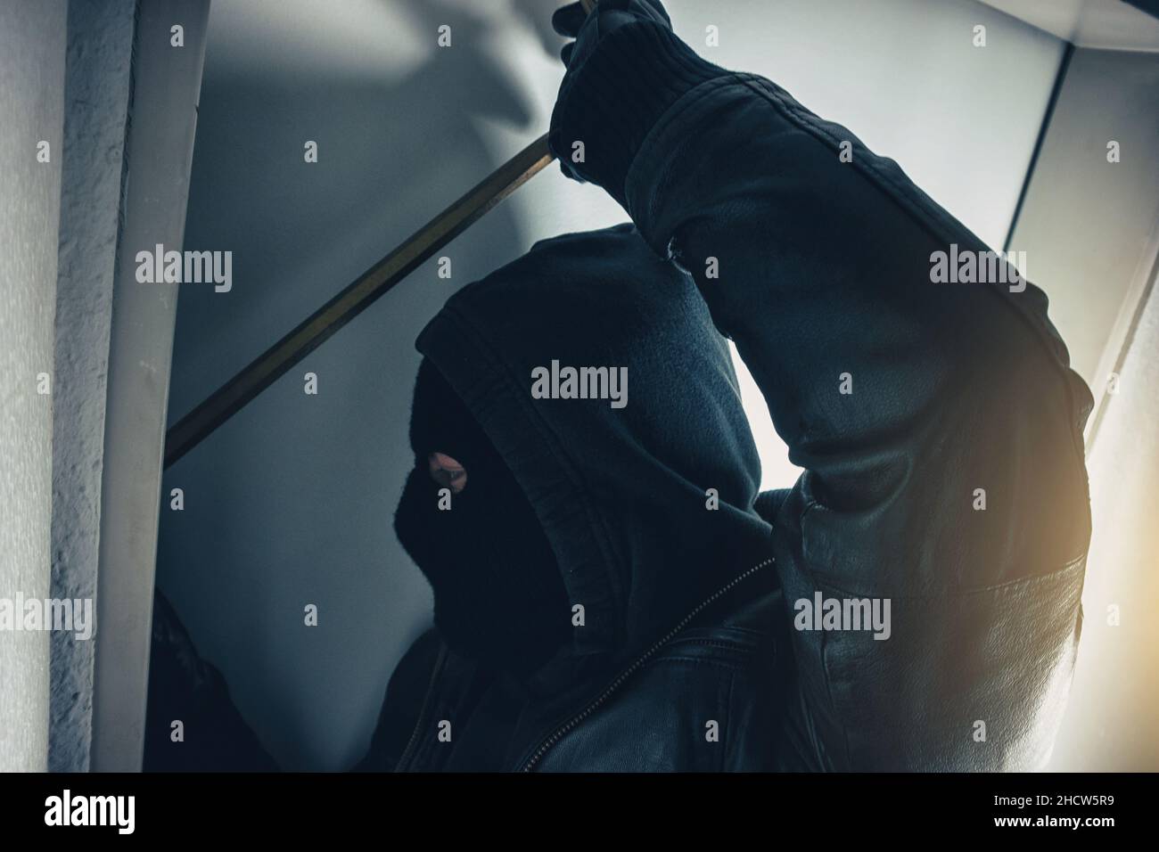 burglar with crowbar breaking and entering a victim's home at night ...