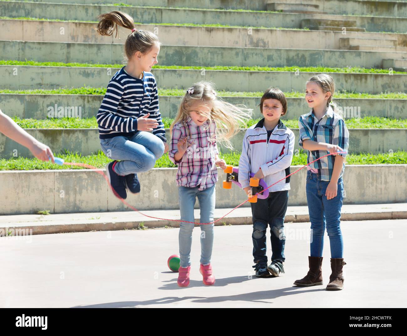 Girl jumping while jump rope game with friends Stock Photo - Alamy